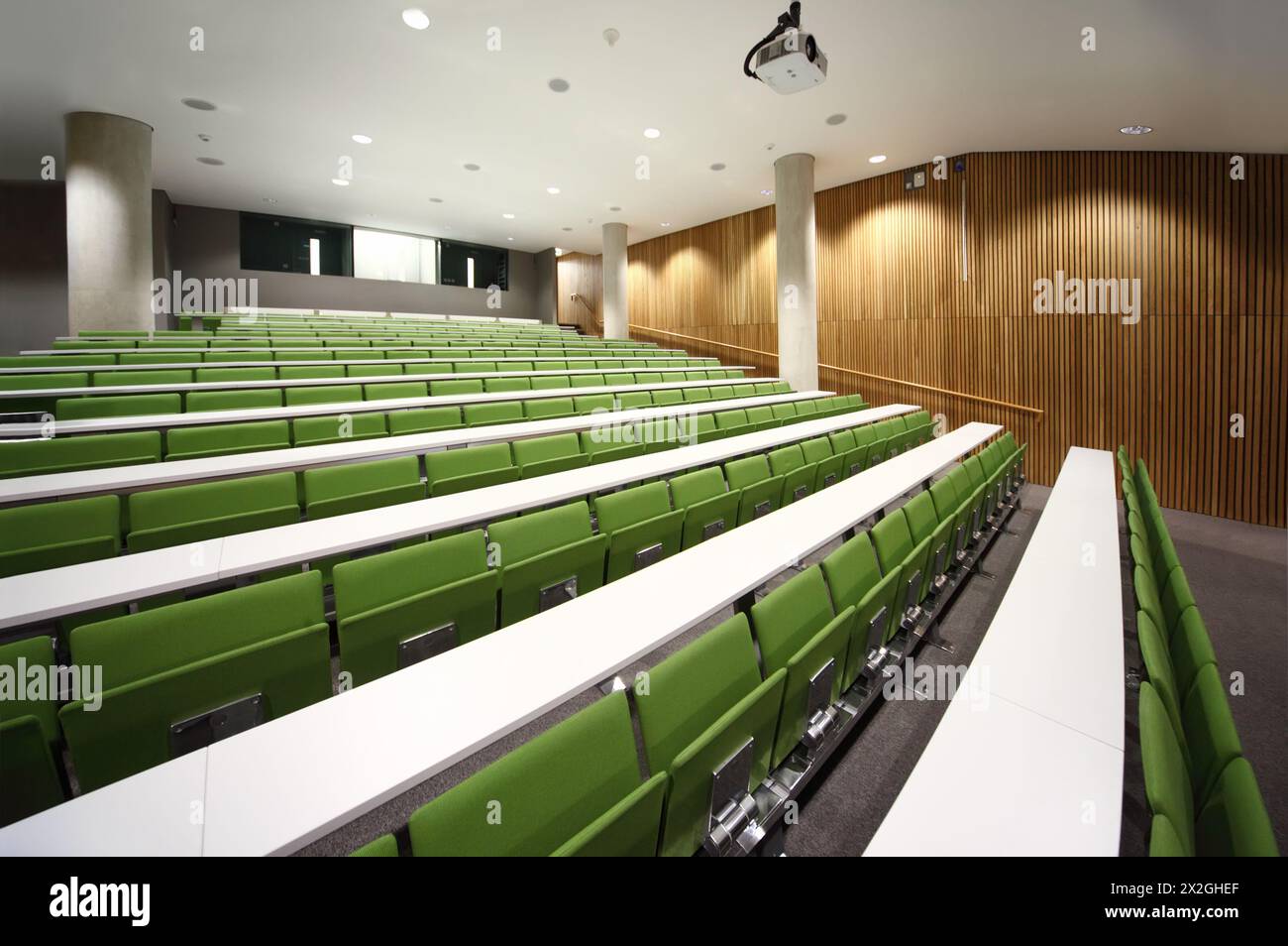 large auditorium with rows of green seats and white tables Stock Photo ...