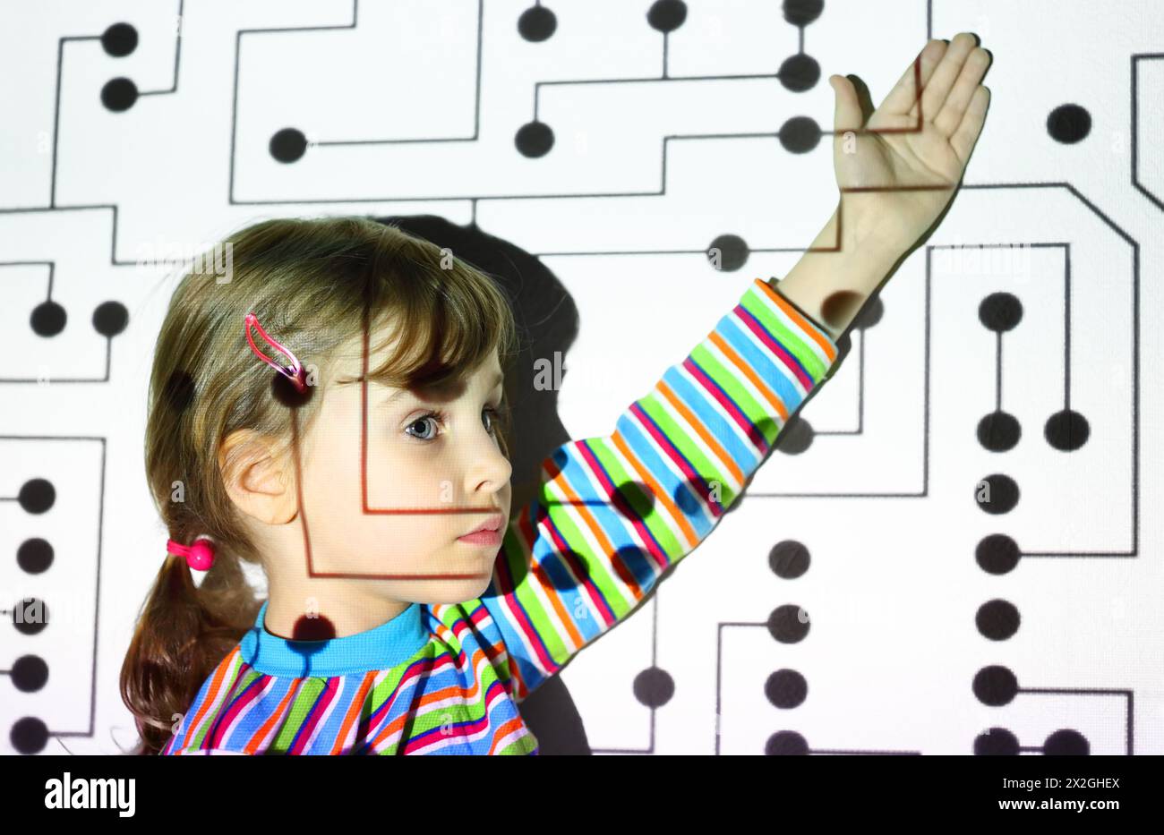 little girl in striped shirts shows on black circle on circuit, board ...