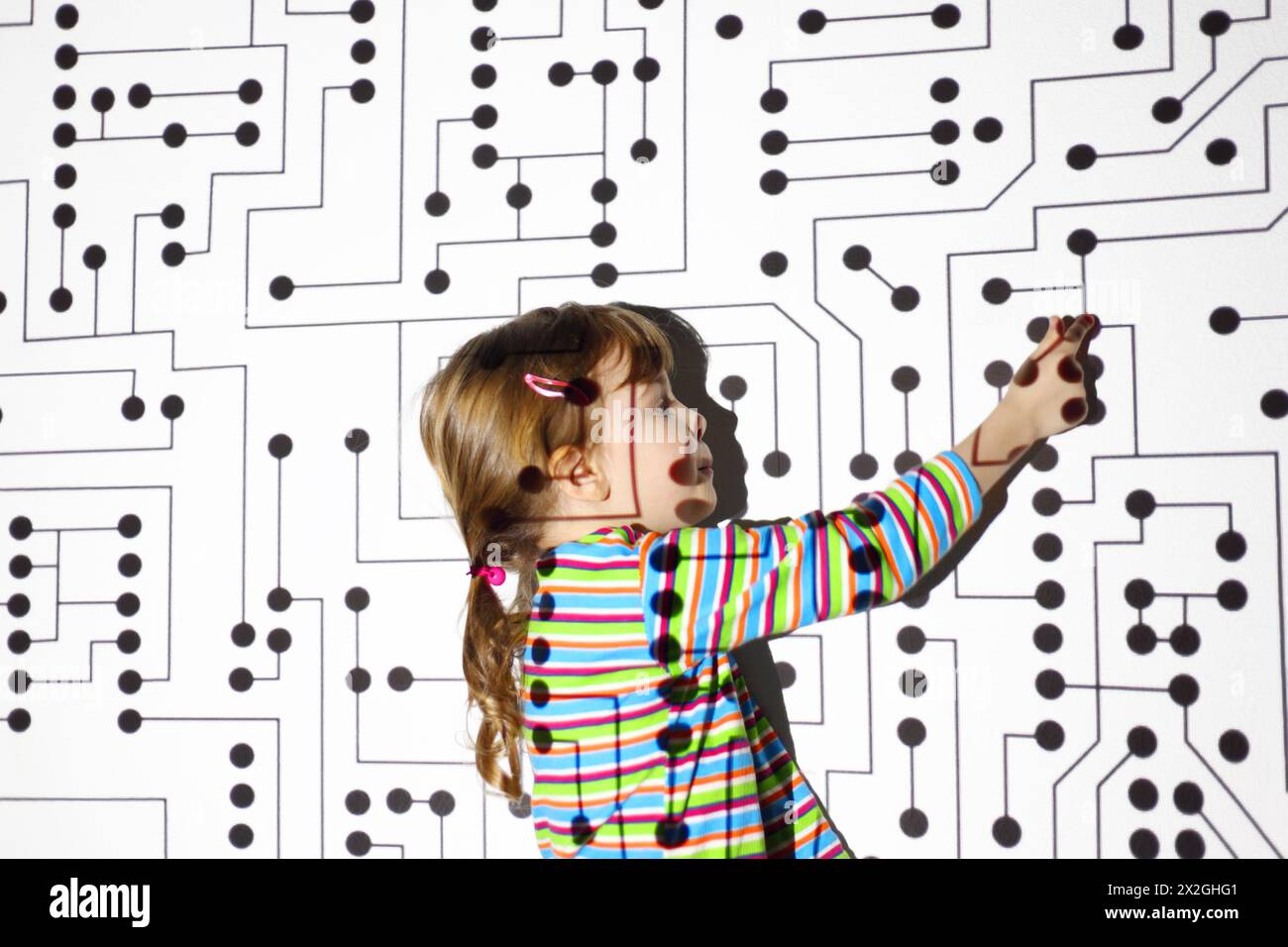 little girl in striped shirts shows on black circle on circuit, board ...