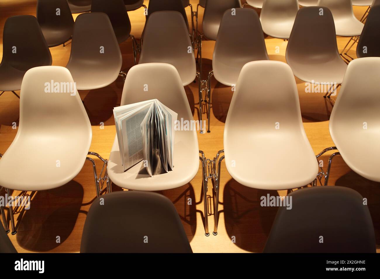several rows of white plastic chairs; brochure standing on chair Stock ...
