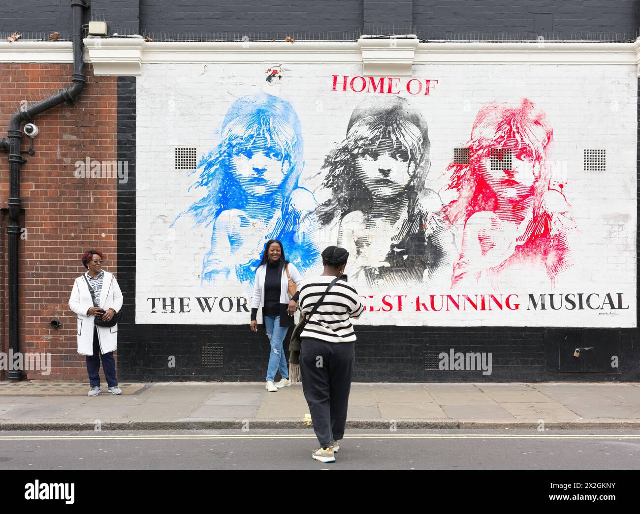 Tourists take a photo in front of a painting of Les Miserables on a ...