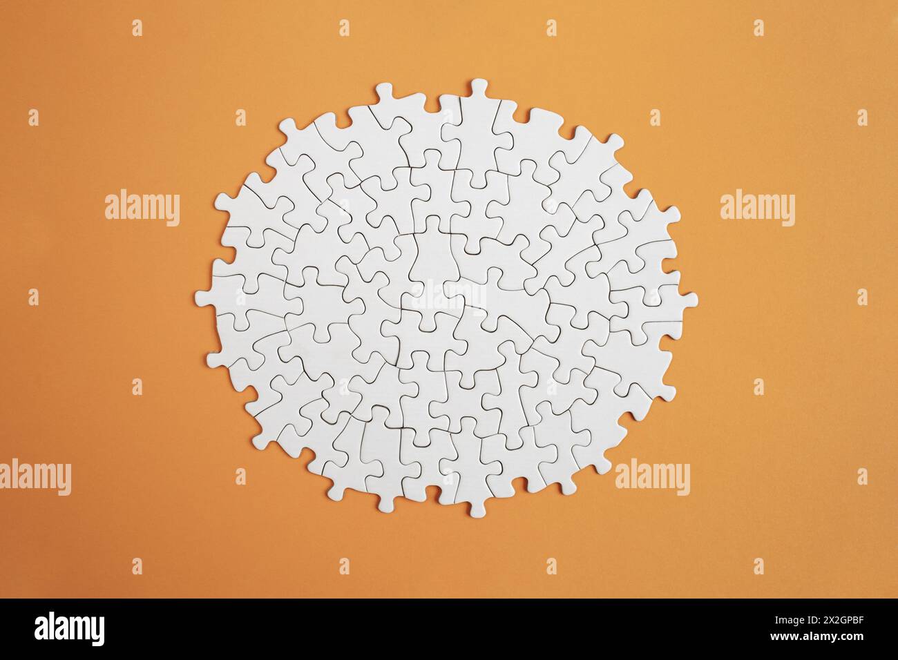 Plain white jigsaw puzzle on orange color background, oval shaped frame ...