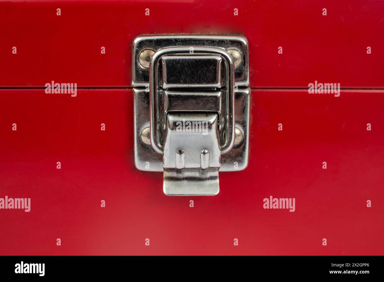 Stainless steel snap lock on a red metallic case, closed lid of a red ...