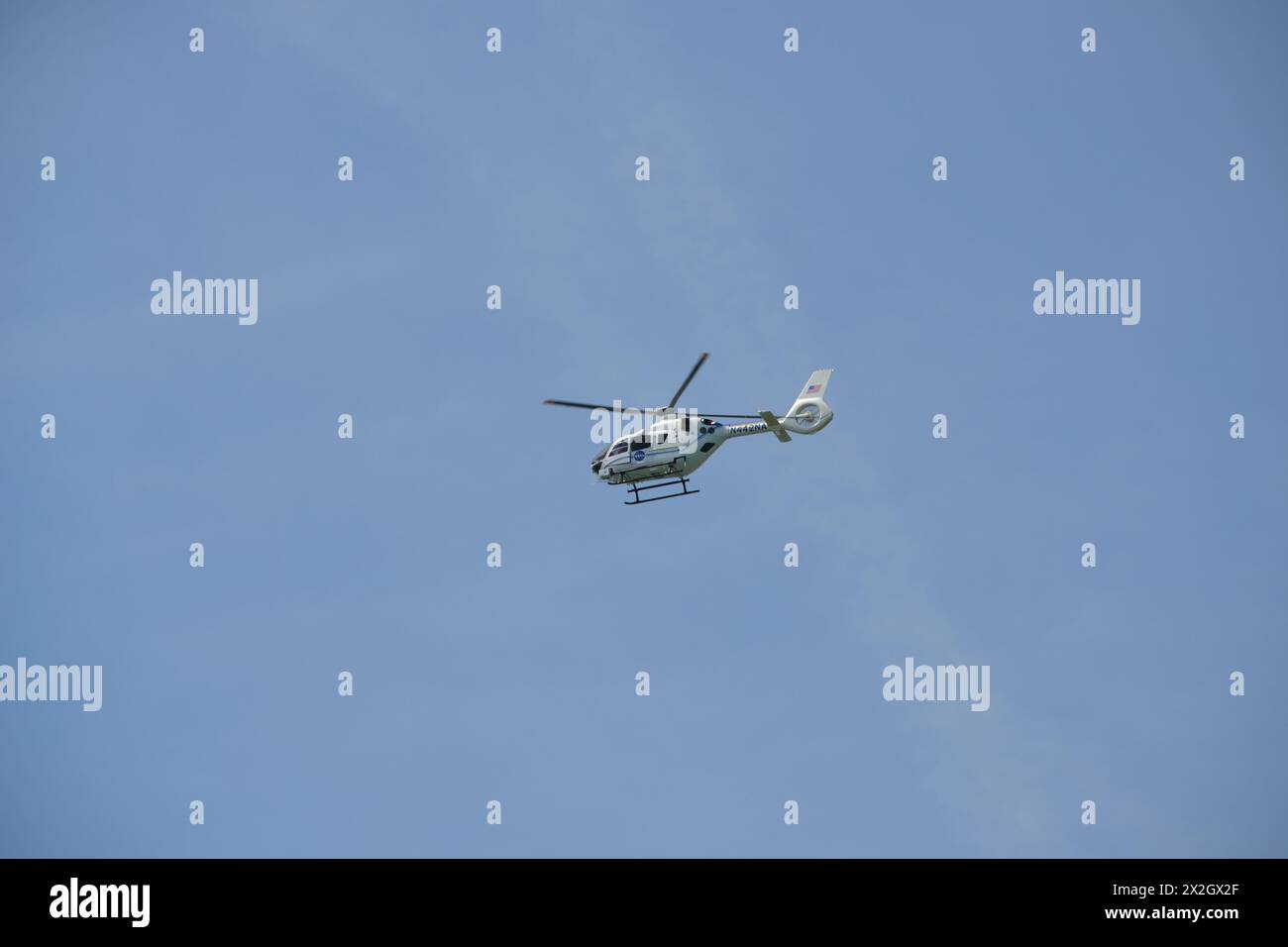 A NASA helicopter soars against the hazy blue backdrop of the sky above ...