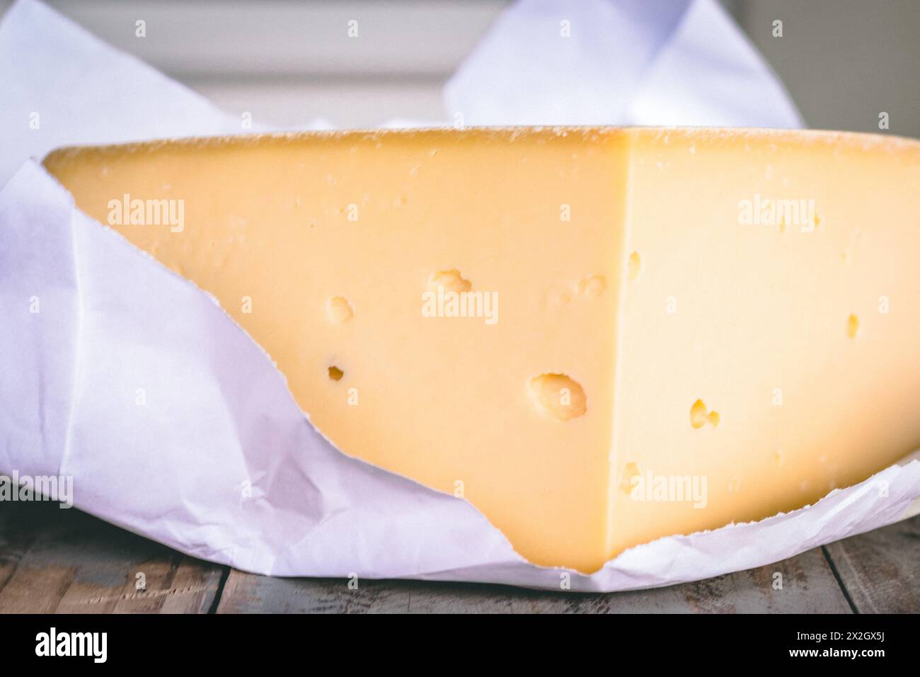 Rustic wedge of Apline style cheese with eyes in paper Stock Photo - Alamy