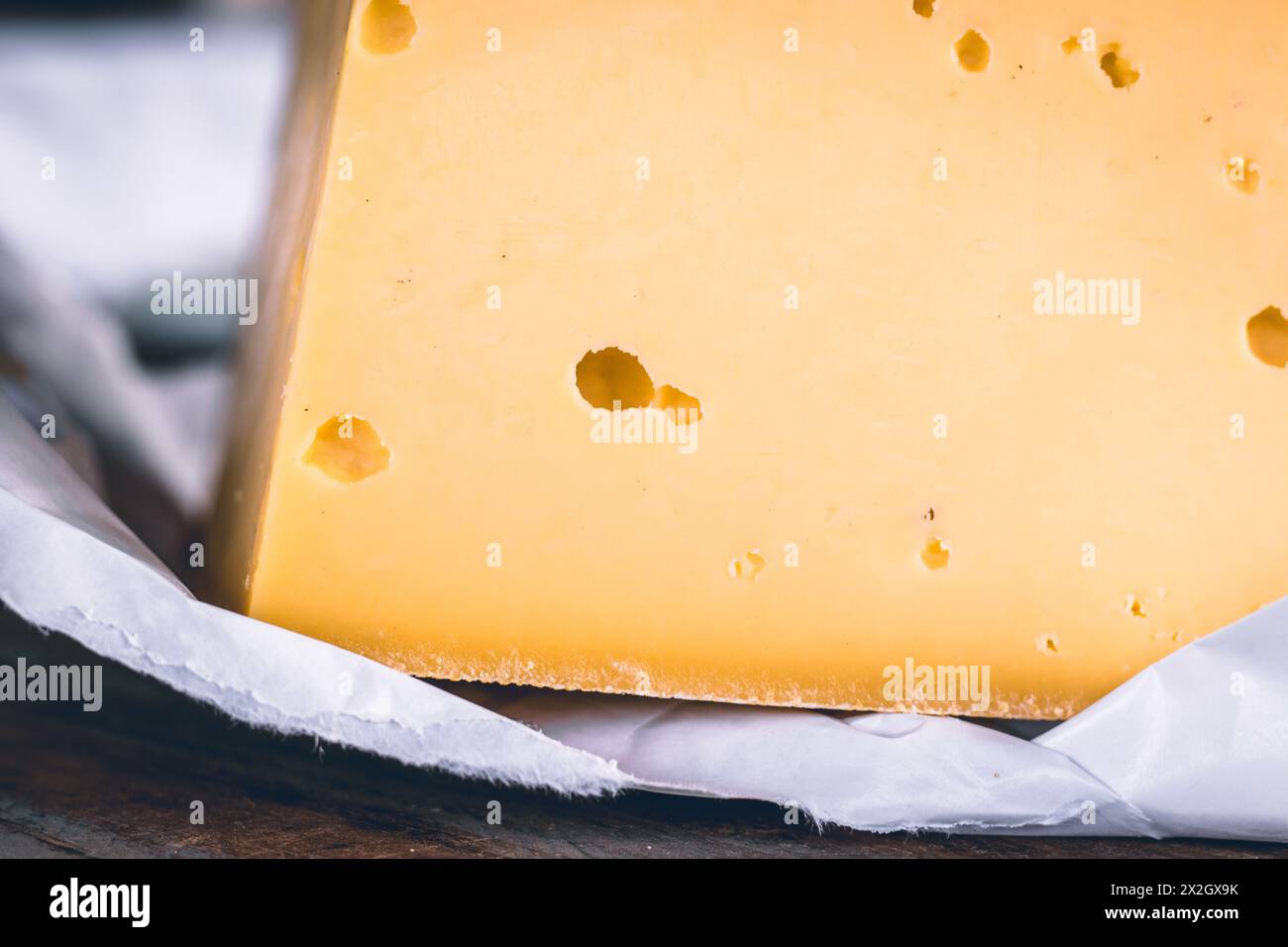 Rustic wedge of Apline style cheese with eyes in paper Stock Photo - Alamy
