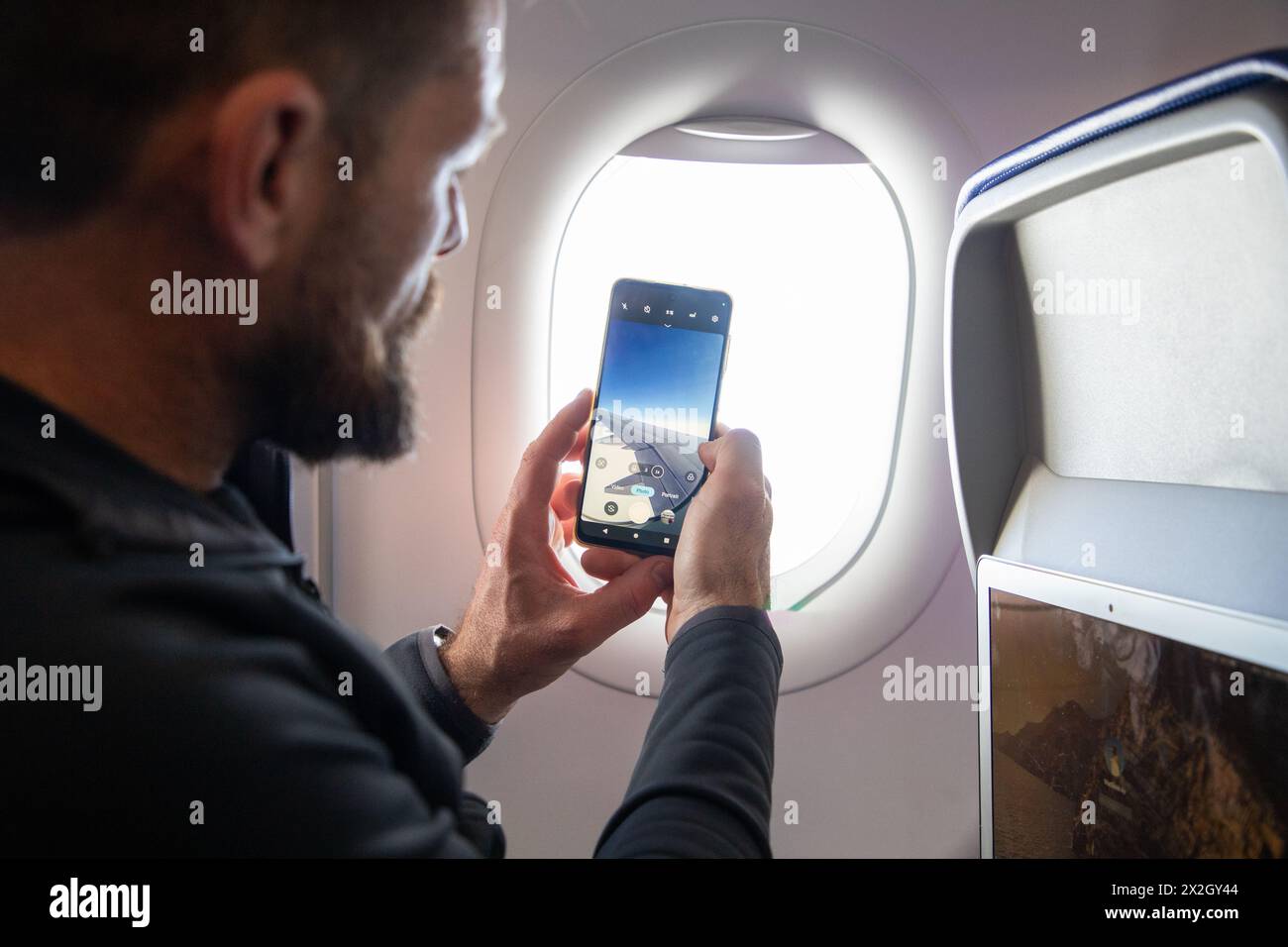 man taking photos through plane window Stock Photo - Alamy