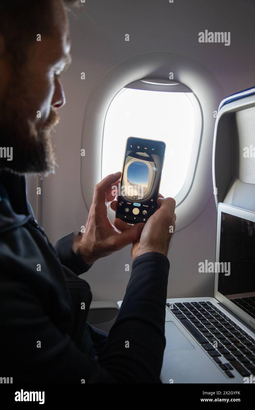 man taking photos through plane window Stock Photo - Alamy