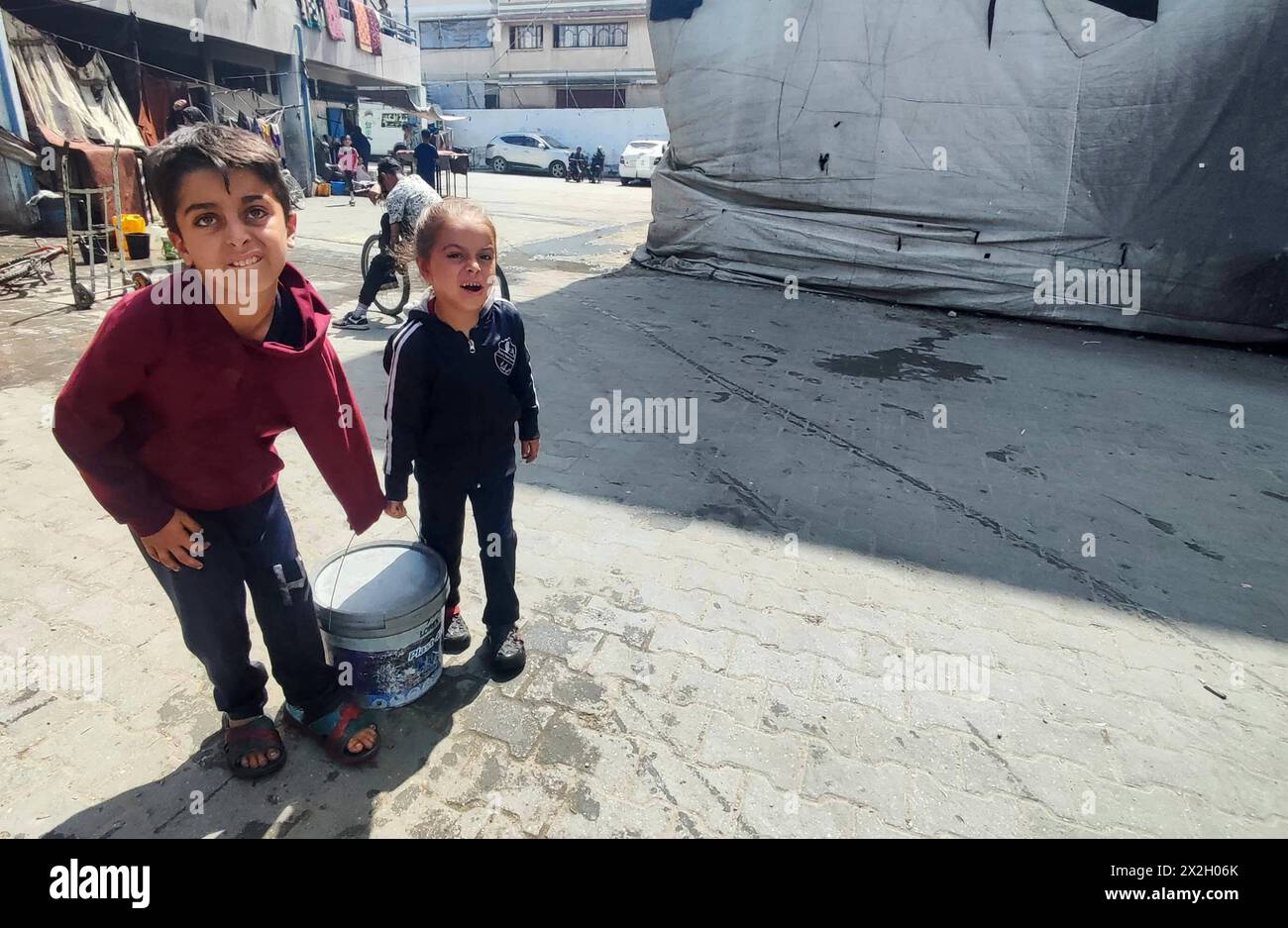 Displaced Palestinians line up to fill their containers with water in ...