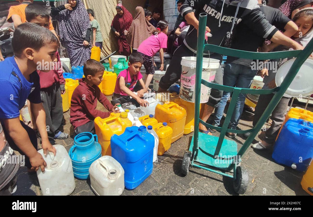 Displaced Palestinians line up to fill their containers with water in ...