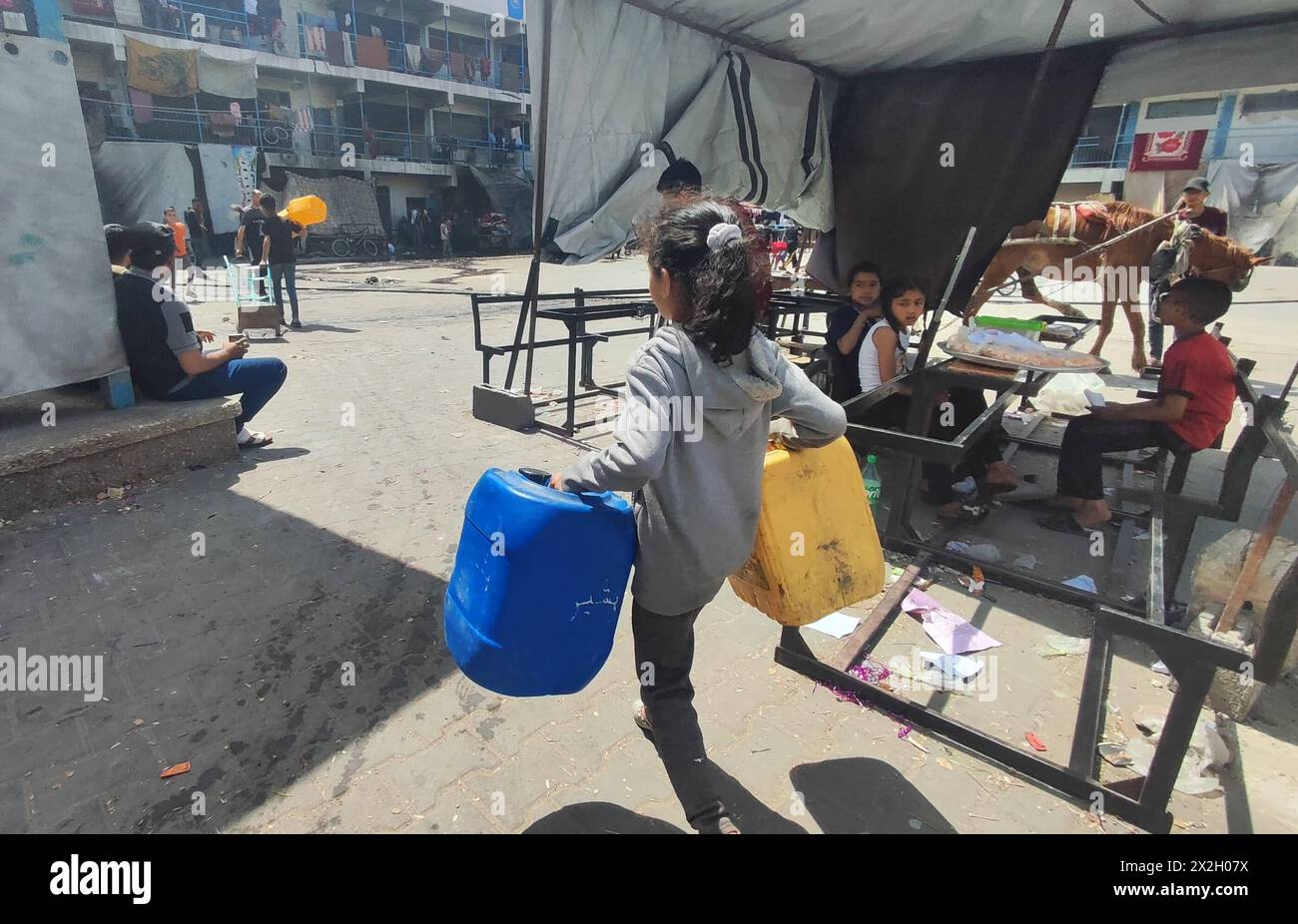 Displaced Palestinians line up to fill their containers with water in ...