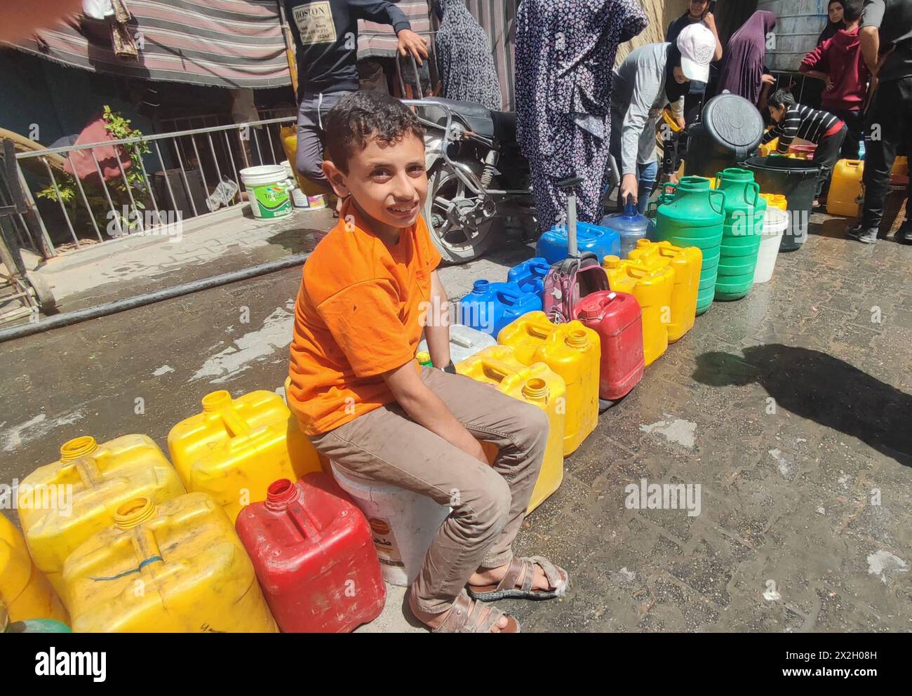 Displaced Palestinians line up to fill their containers with water in ...