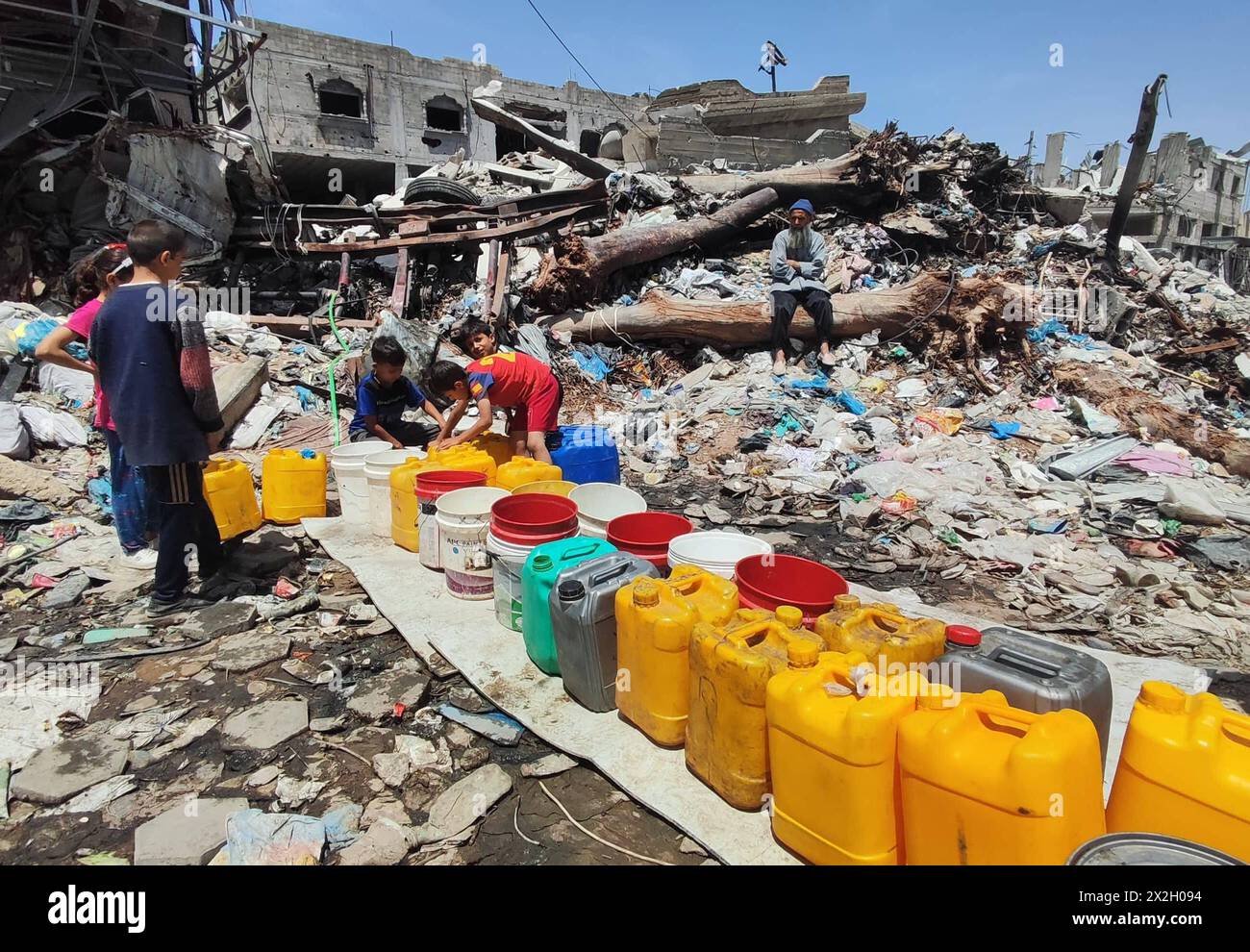 Displaced Palestinians line up to fill their containers with water in ...