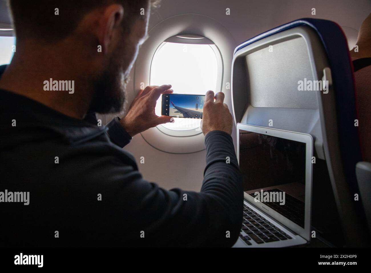 man taking photos through plane window Stock Photo - Alamy