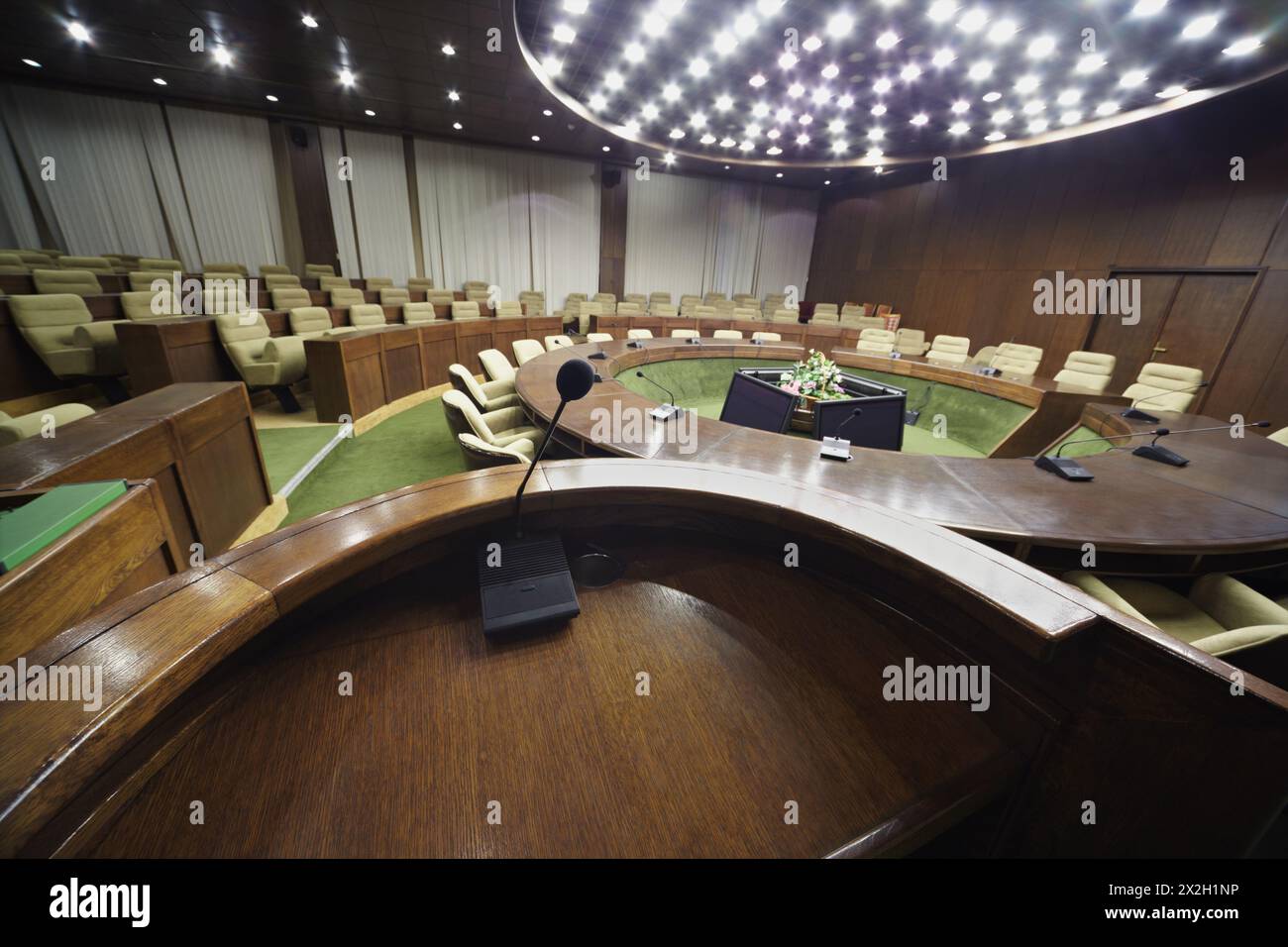 View on the auditorium with round oak table and beige armchairs around ...