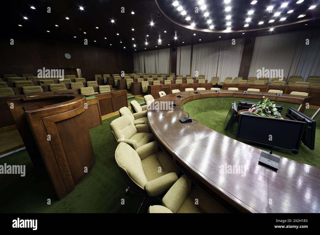 Conference hall with round table and rows of chairs for participants ...