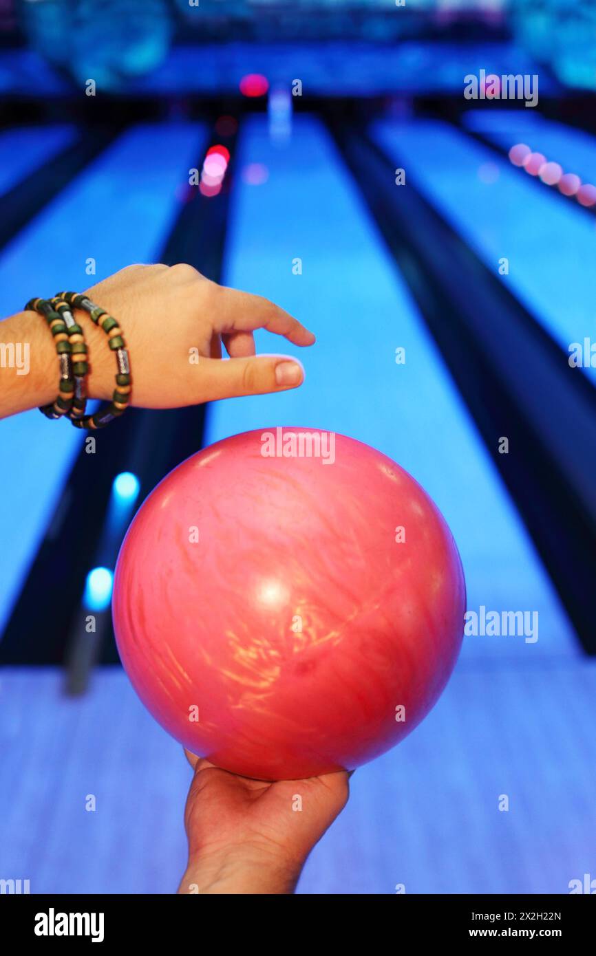 Hands of man, which holds red ball and prepares to throw in bowling ...