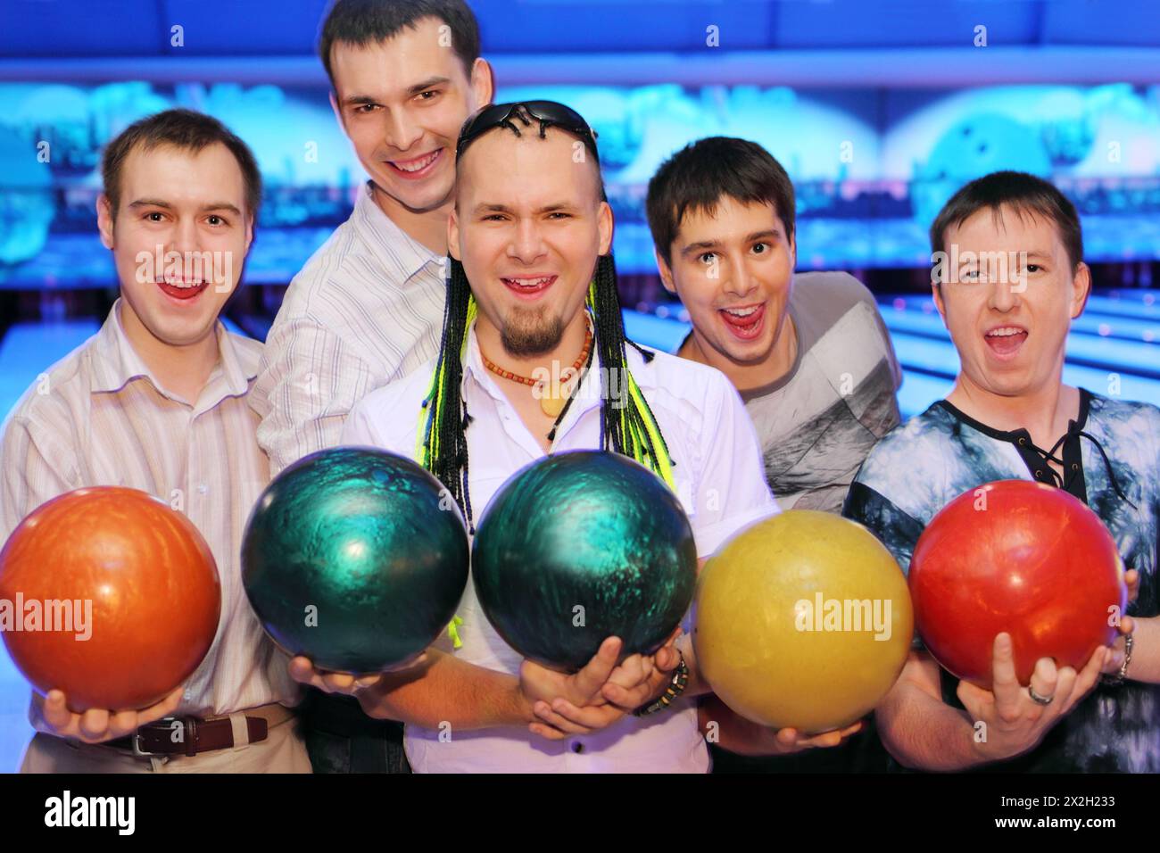 Five happy men hold balls in bowling club; friends relax together Stock ...