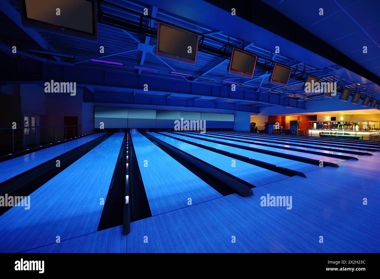 Empty bowling club, lot of bowling lanes with skittles, blue lighting ...