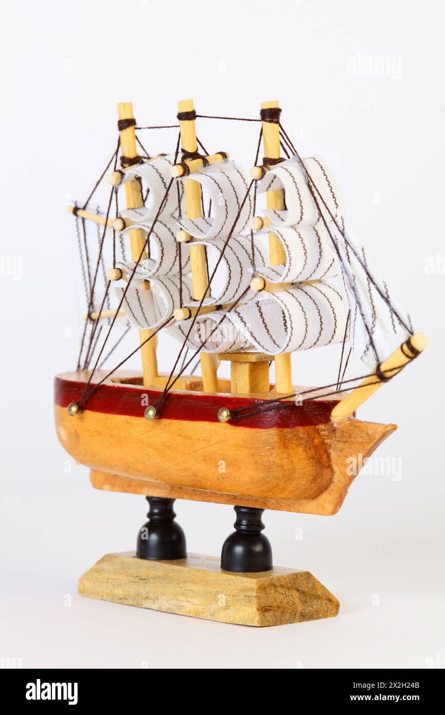 Small wooden model of sailing ship with rigging and white sails on ...