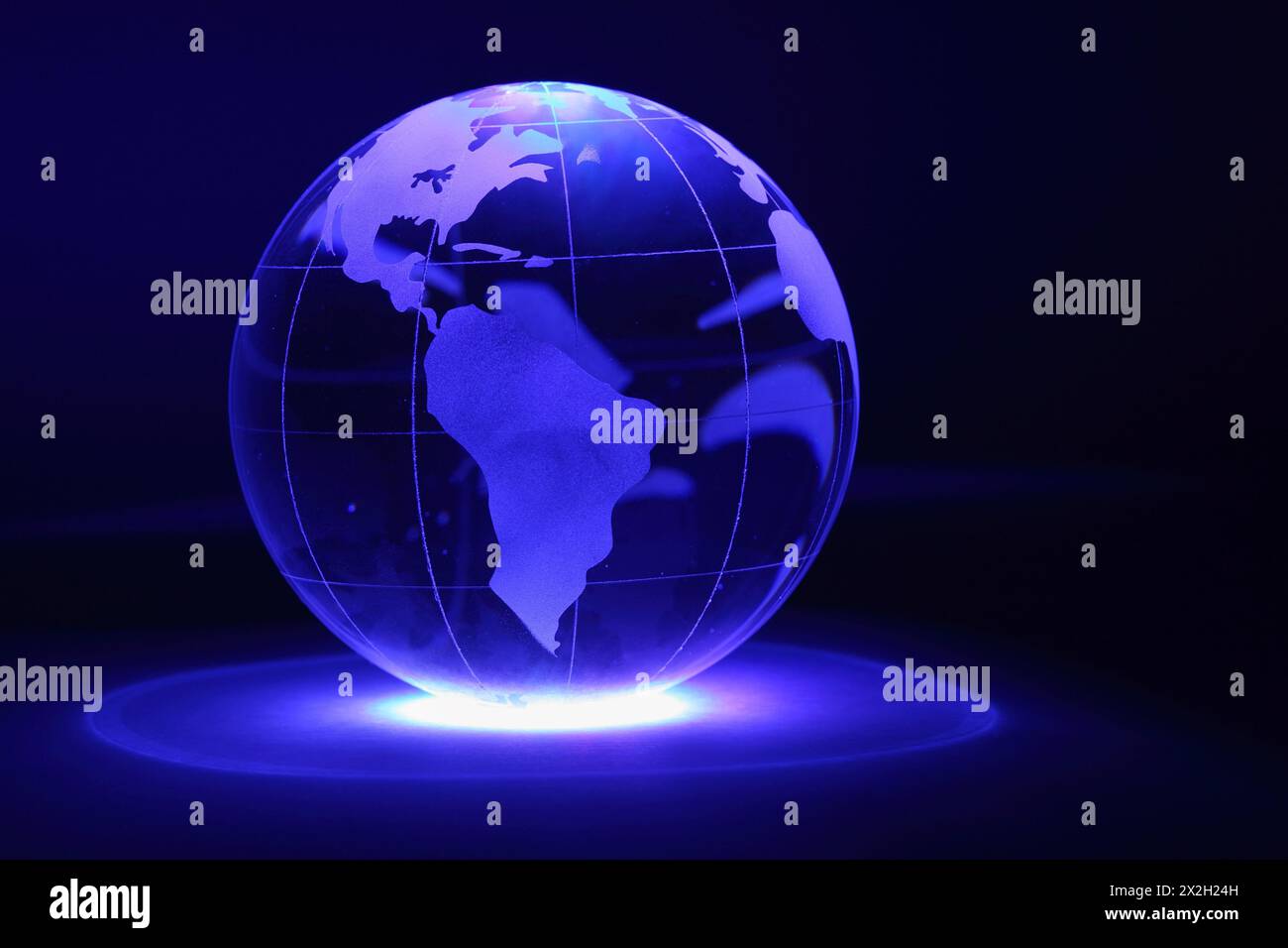 Small glass globe is illuminated by blue light from below in dark ...