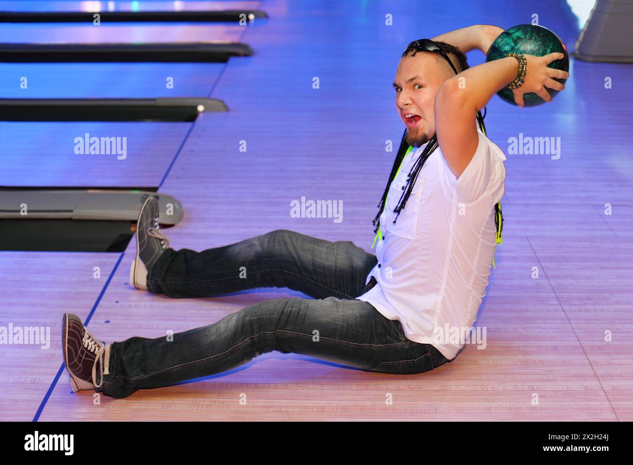 Young man sits on floor and prepares to throw in bowling club Stock ...