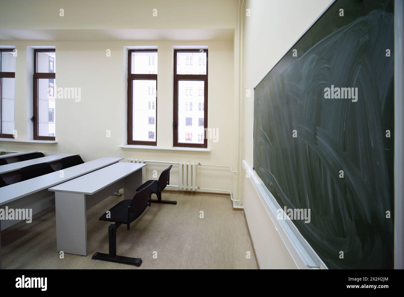 Big green school board inside empty beige classroom with wooden school ...
