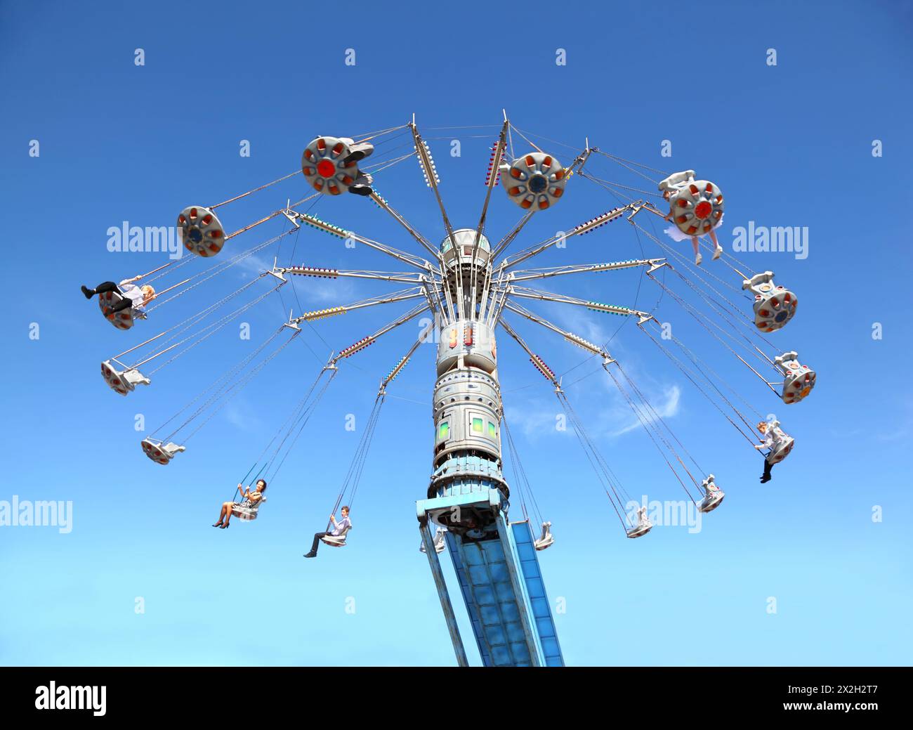 Happy people on swinging circular chained carousel at high blue sky ...