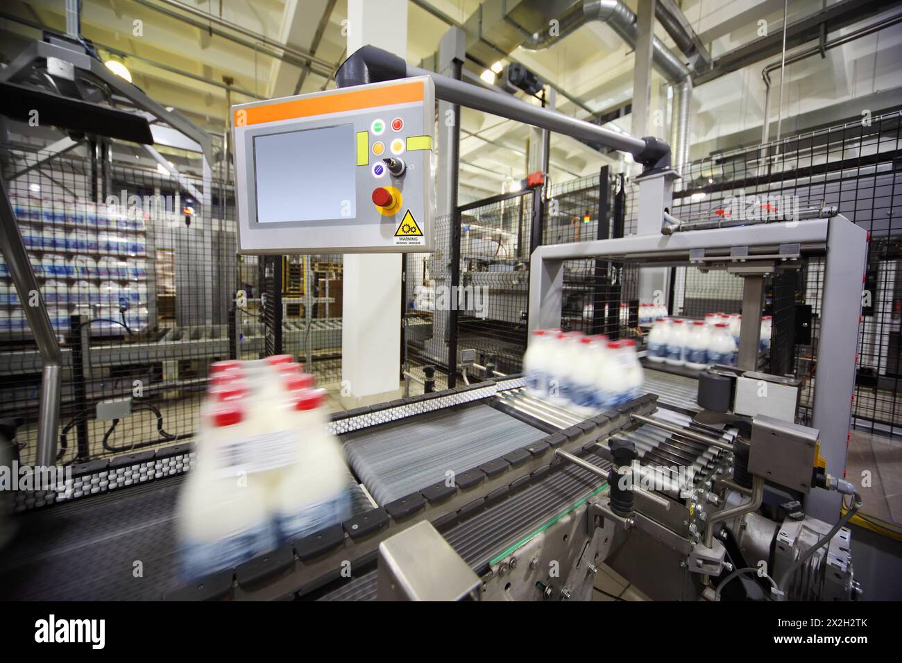 Conveyor with wrapped milk bottles at big factory; display of control ...