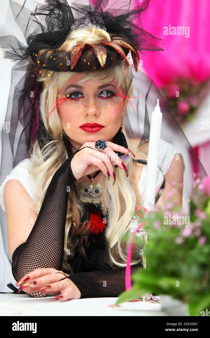 young bride wearing black net gloves and unusual hat sits at table with ...