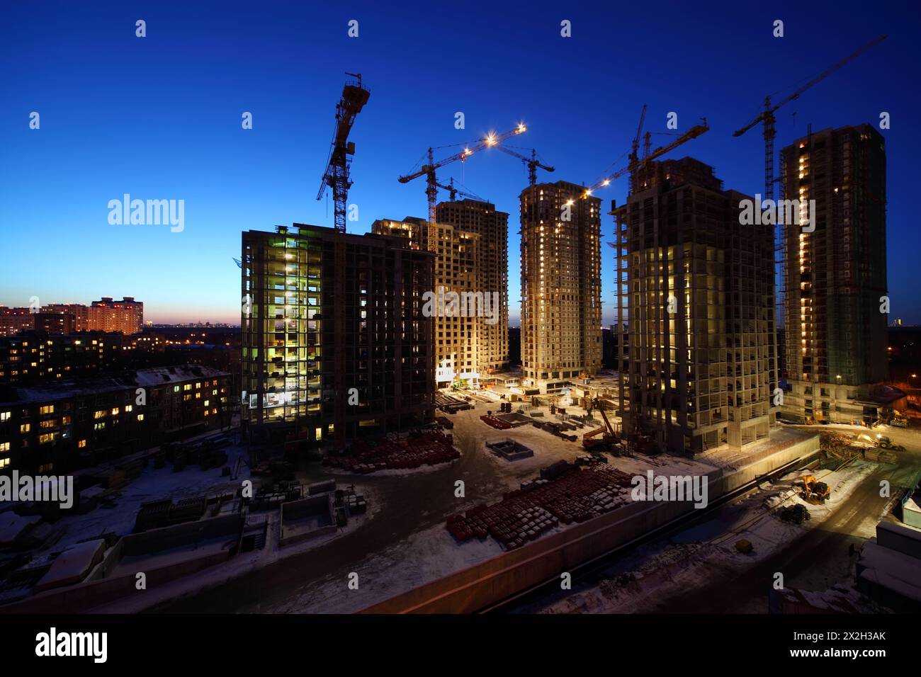 Seven high buildings under construction with cranes and illumination at ...