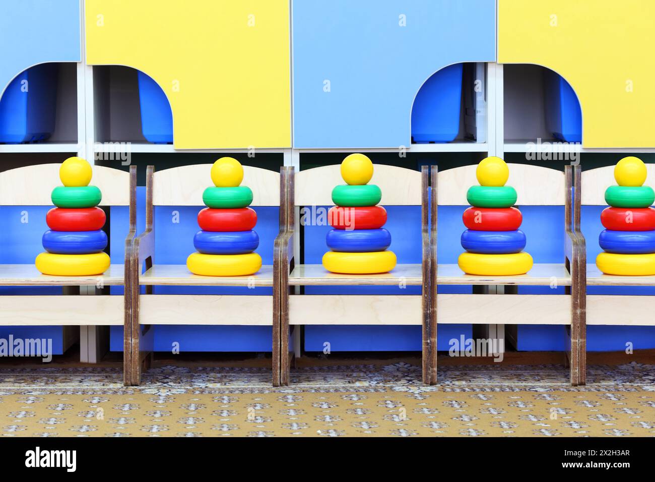 Five colorful pyramid toys stand at small chairs in kindergarten Stock ...