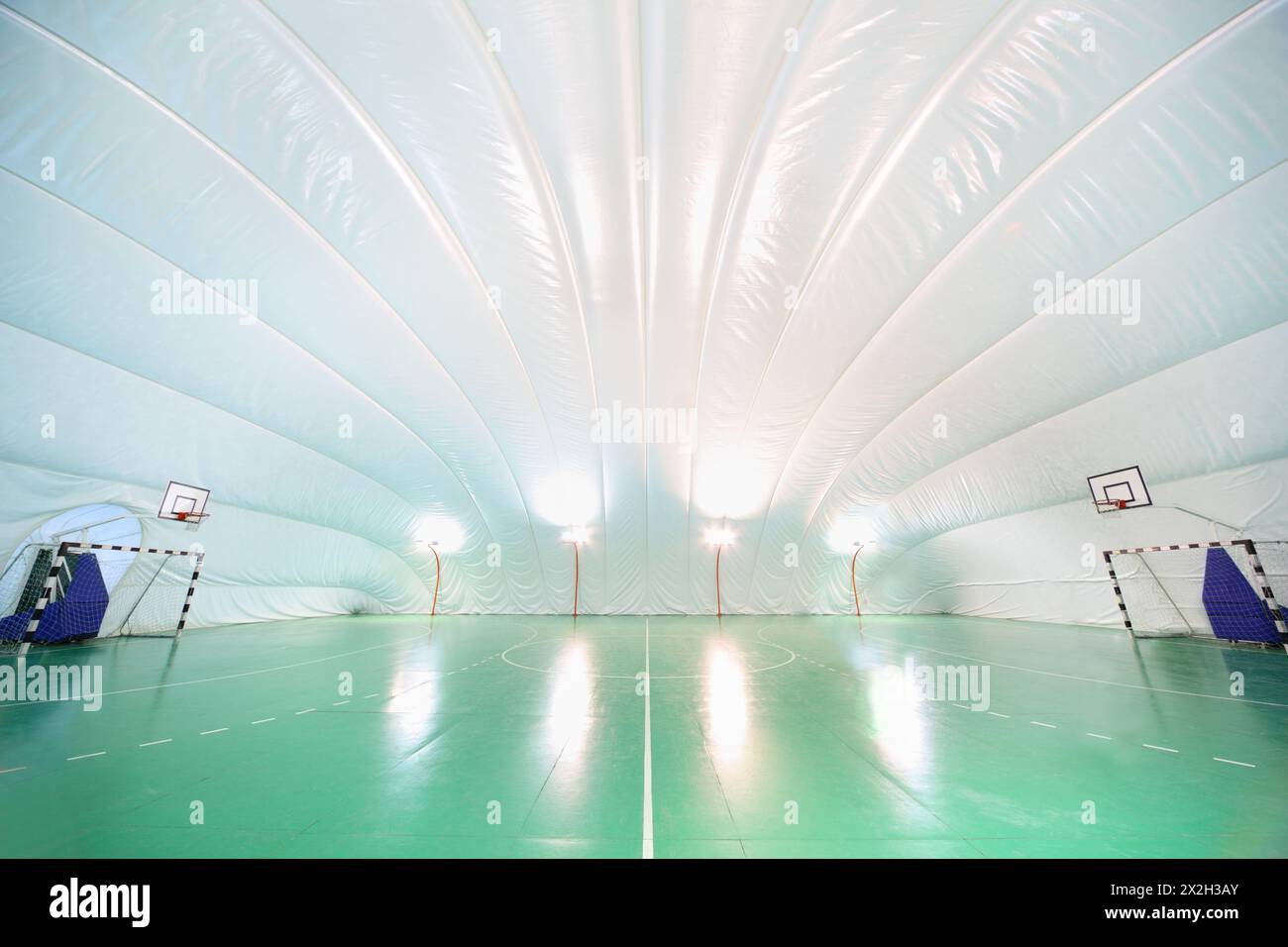 Empty indoor sports ground, plastic white ceiling and walls, green ...