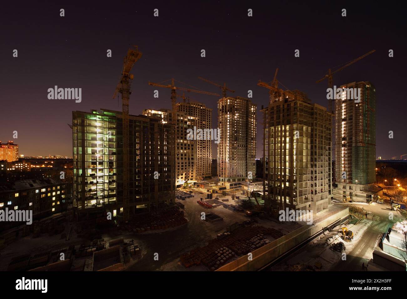Seven high buildings under construction with cranes and illumination at ...