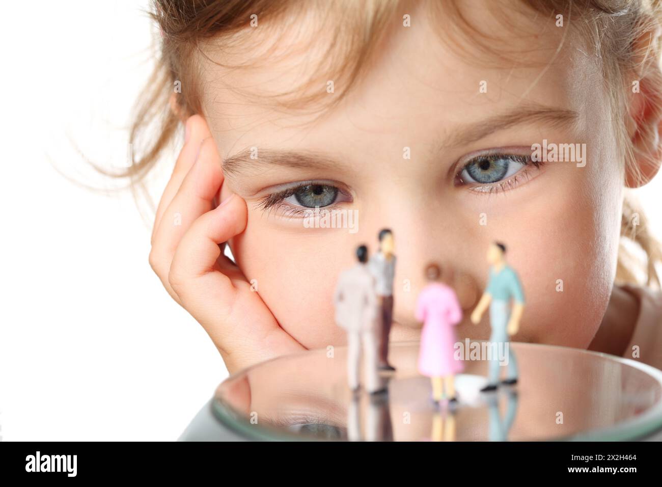 beautiful little girl looks at small toy figures of people isolated on ...