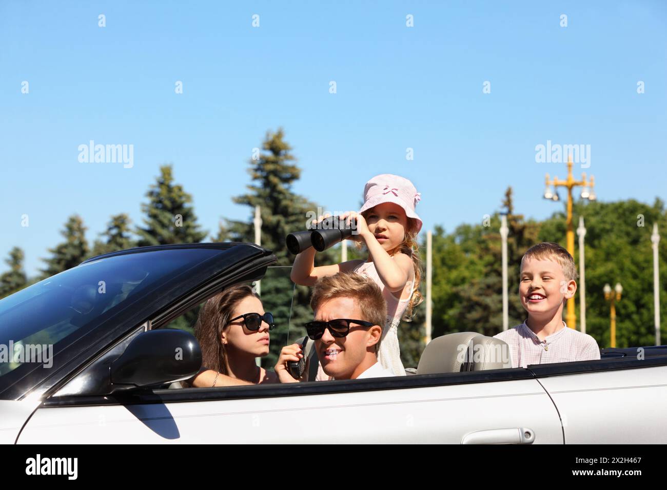 Beautiful father, mother and two children ride in convertible car and ...