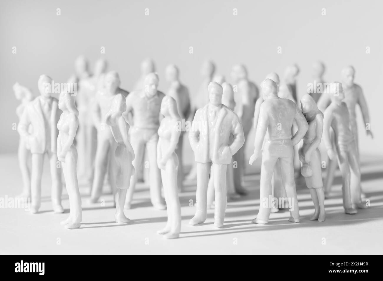 white miniature toy people stand in different poses, men and women on ...
