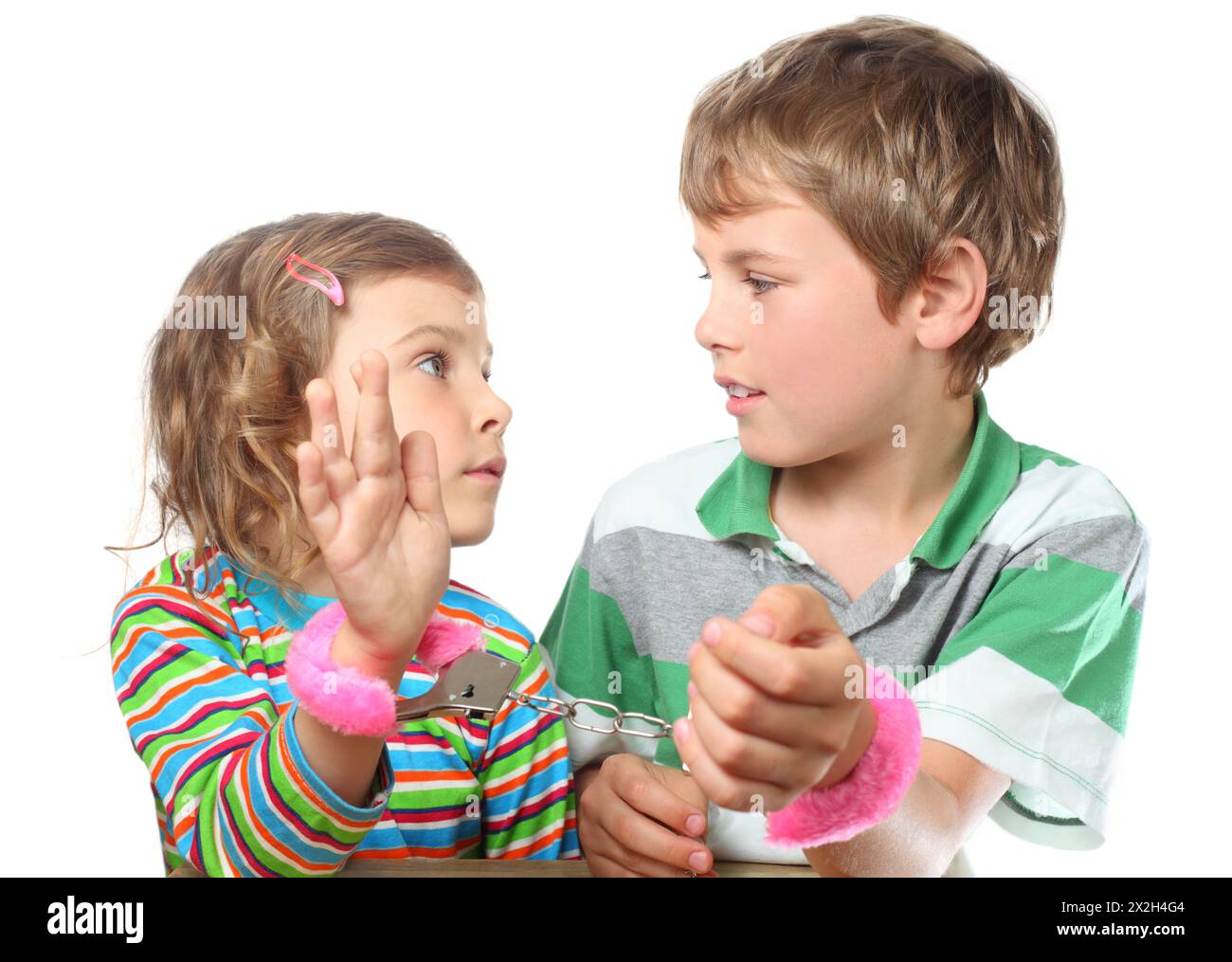 little boy and girl sit at table and related toy handcuffs isolated on ...