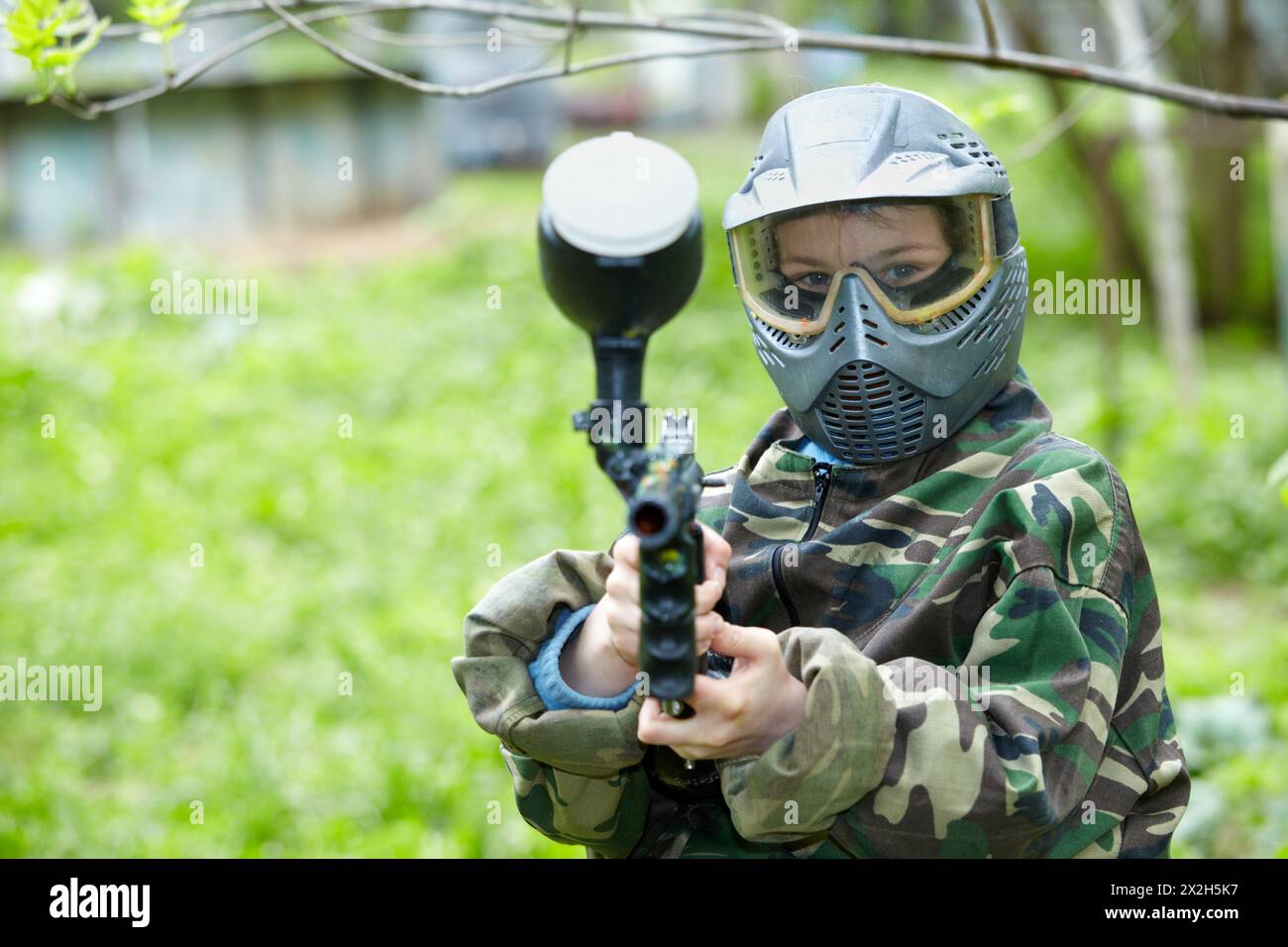 Paintball player in camouflage uniform and protective mask poses ...