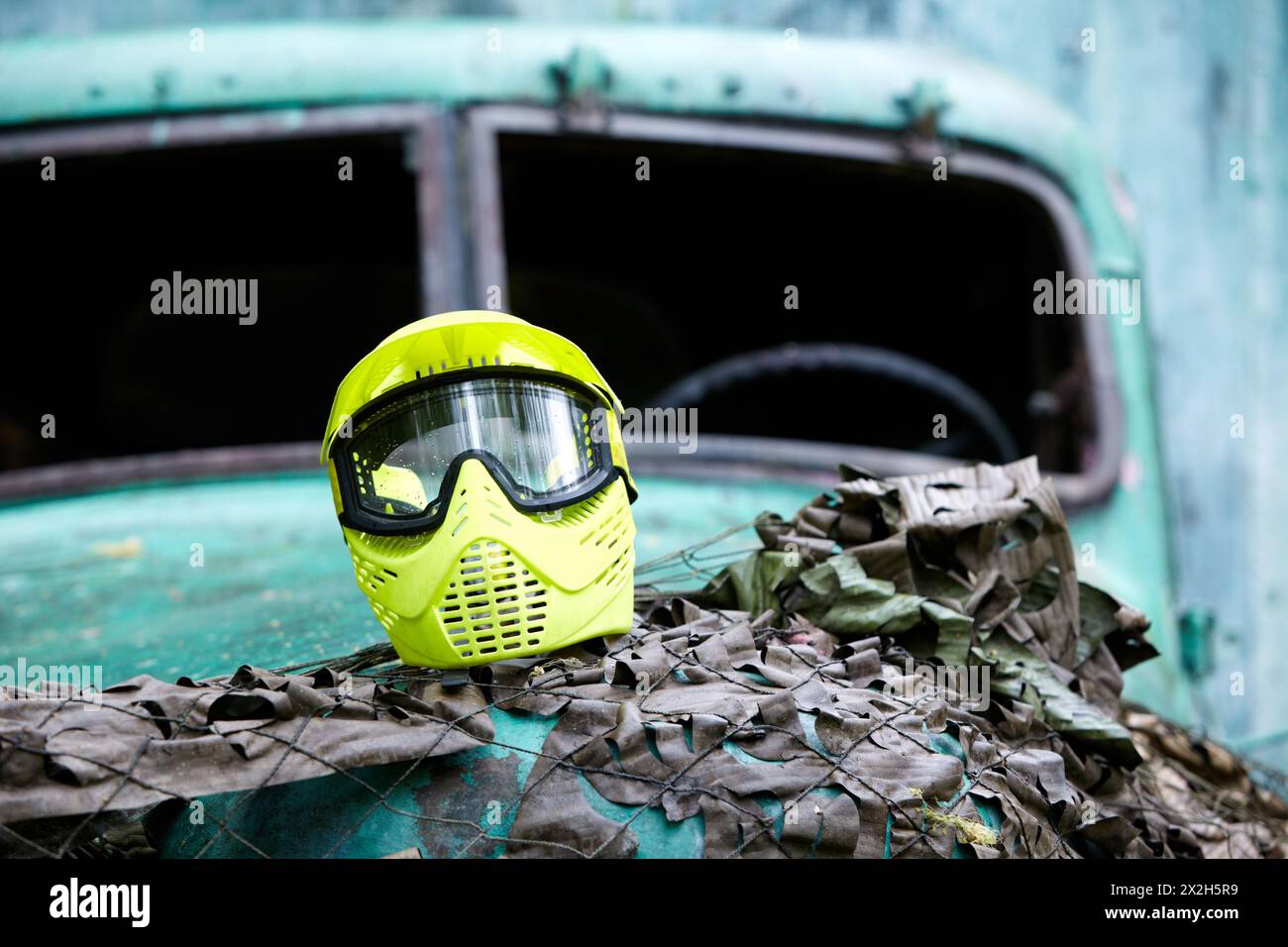 Yellow protective mask for paintball players lies on the hood of an old ...