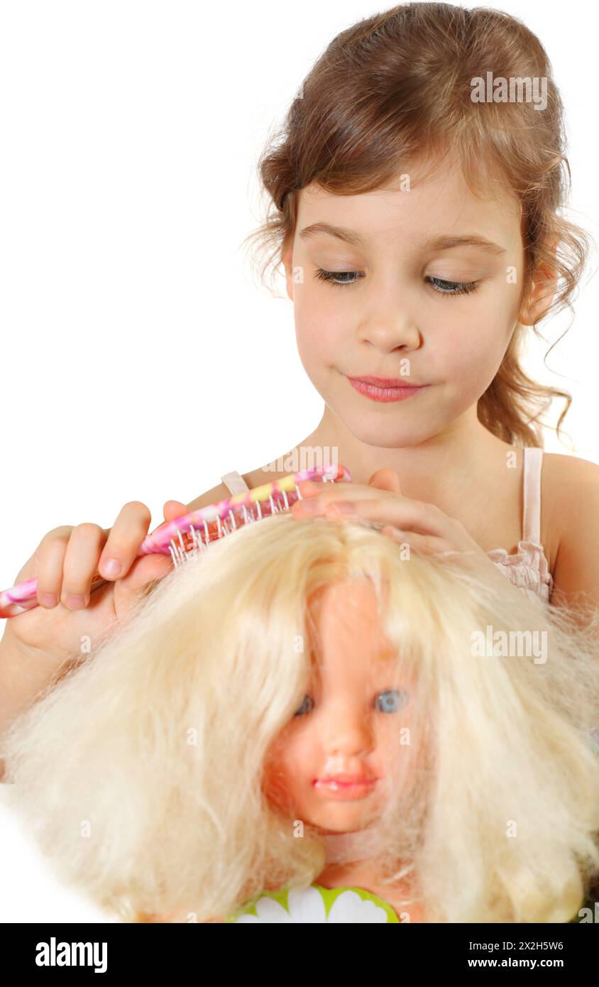 Girl combs doll hair by toy hairbrush isolated on white background ...
