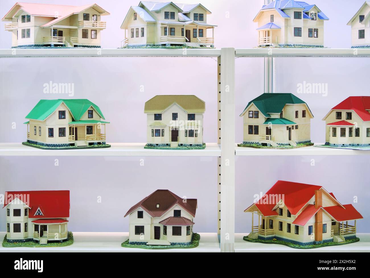 Small different beautiful models of cottages stand on white shelves ...