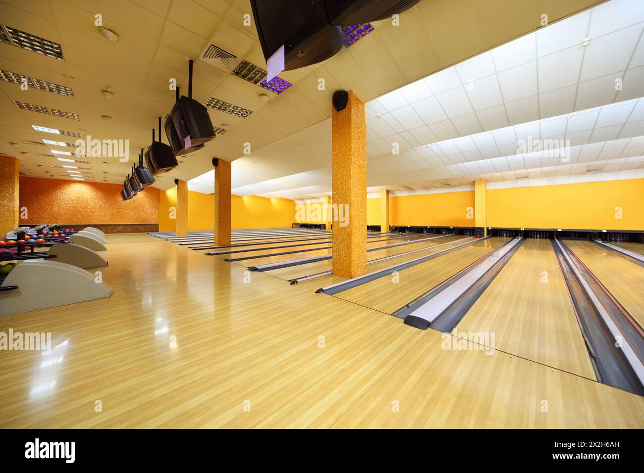Empty bowling club, lot of bowling lanes with skittles, yellow walls ...