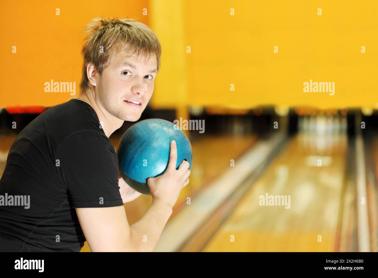 Young man wearing in black t-shirt holds blue ball and prepares to ...