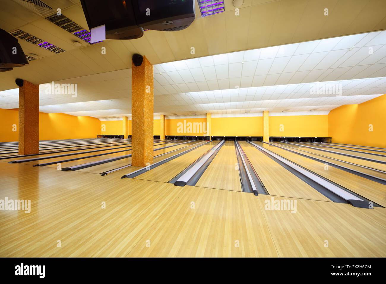 Empty light bowling club, lot of bowling lanes, yellow walls Stock ...