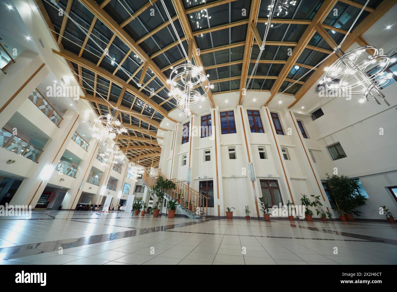 High empty hall with a wooden roof timbers and with a glass roof, lit ...