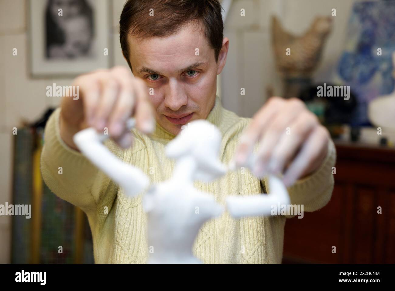 Sculptor attach arms to armless plaster statuette and critically ...