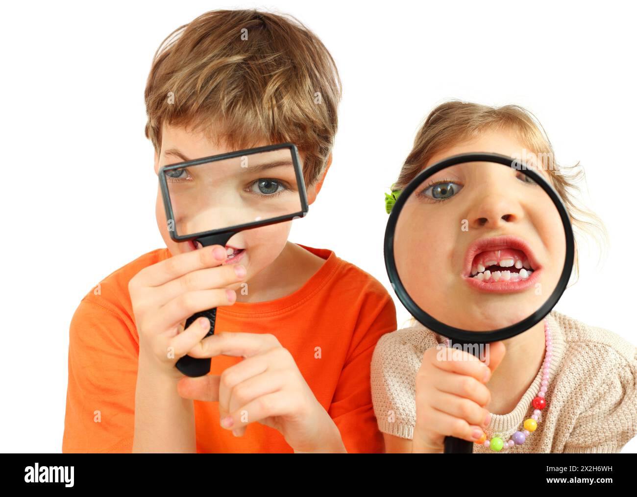 Brother and sister looking through magnifying glasses isolated on white ...