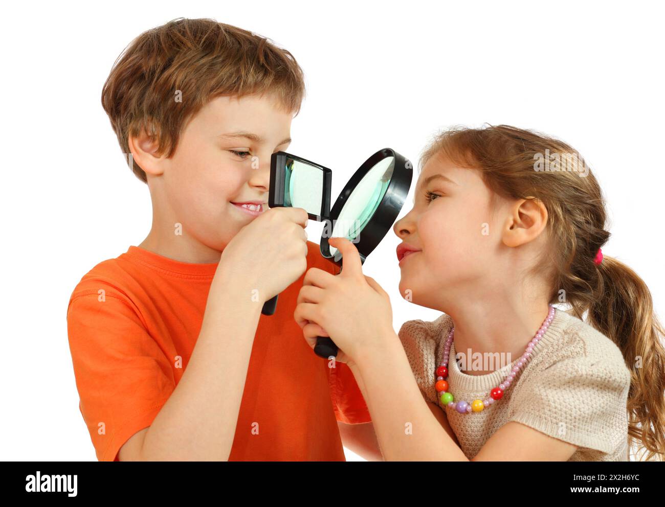 Brother and sister looking at each other through magnifying glasses ...