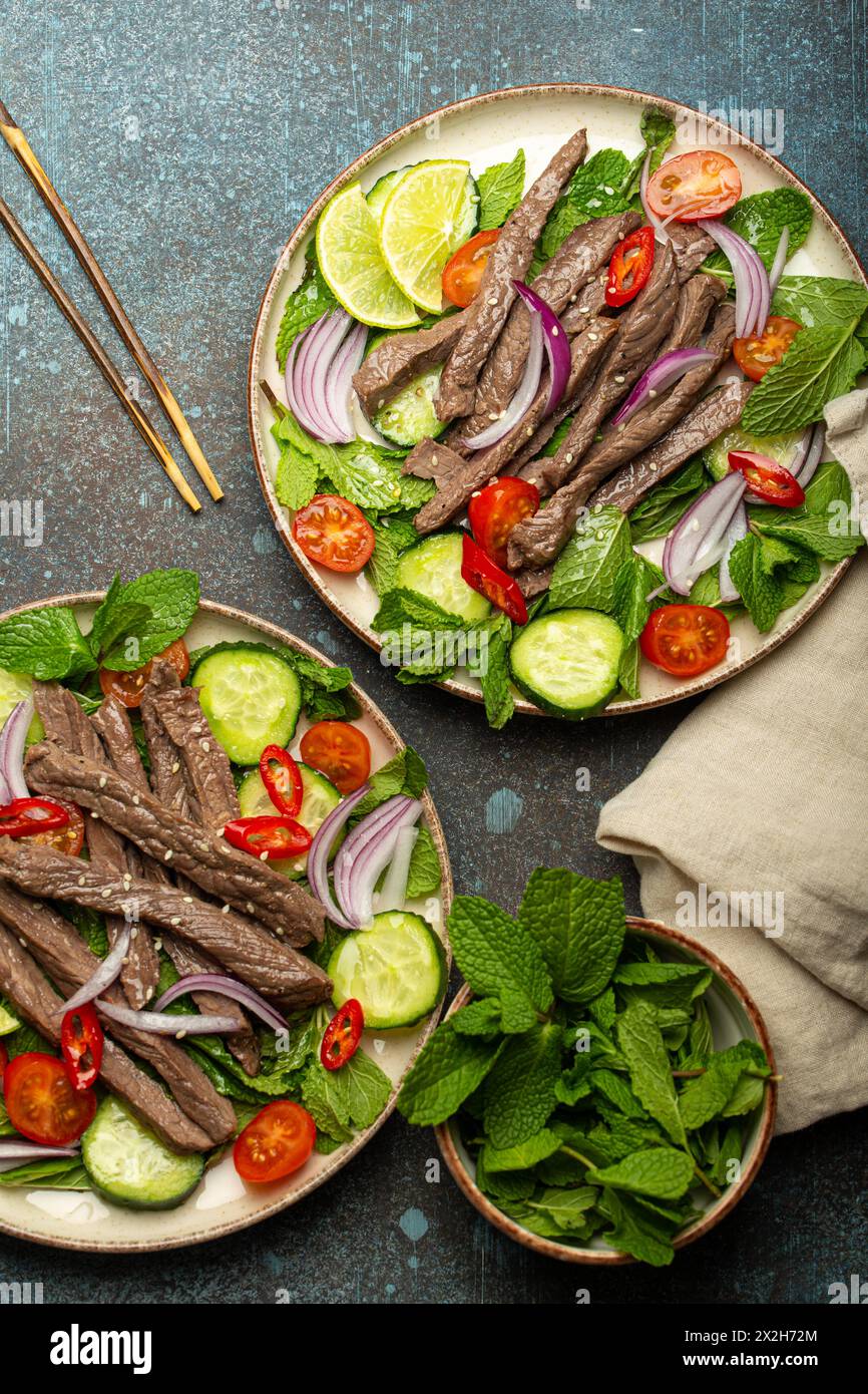 Two plates with traditional Thai beef salad with vegetables and mint ...